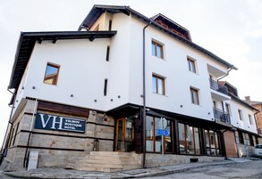 Um hotel de dois andares com uma placa indicando 'Velinov Boutique Hotel'.