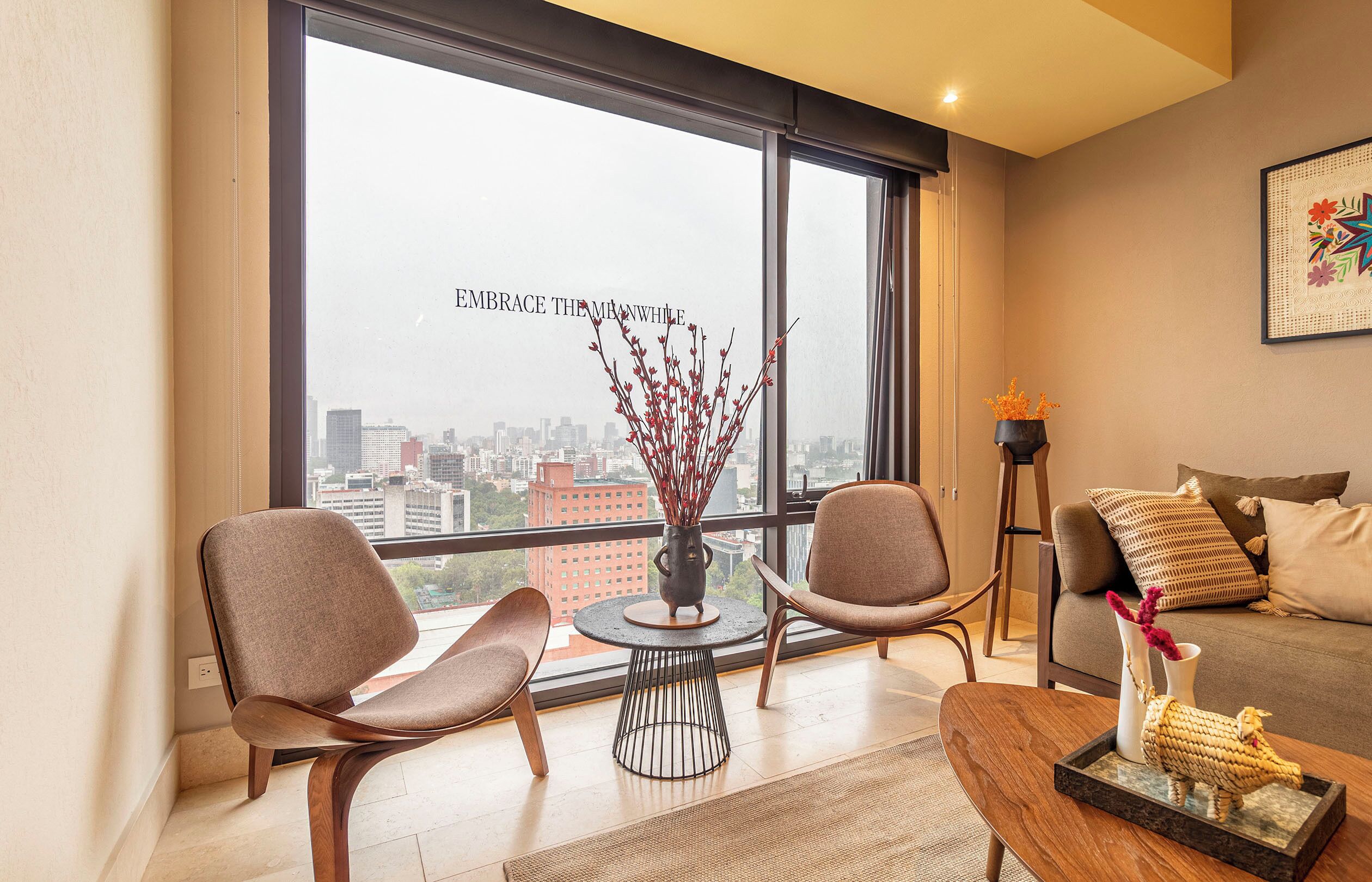 Uma sala de estar moderna com uma grande janela, duas poltronas, uma mesa redonda pequena, um sofá e um vaso decorativo.
