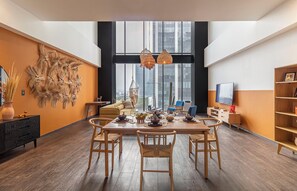 Uma sala de jantar moderna com mesa de madeira, cadeiras e uma grande janela com vista para a cidade.
