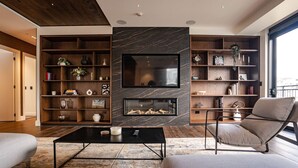 Uma sala de estar moderna com lareira, estantes embutidas, TV de tela plana e um espaço de estar confortável.