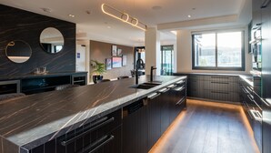 Uma cozinha moderna com bancada de mármore, eletrodomésticos embutidos e uma janela grande que oferece luz natural.