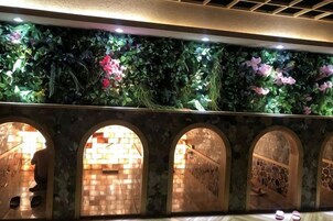 Paredes com um design de folhagem verde, tijolos e três janelas em arco.