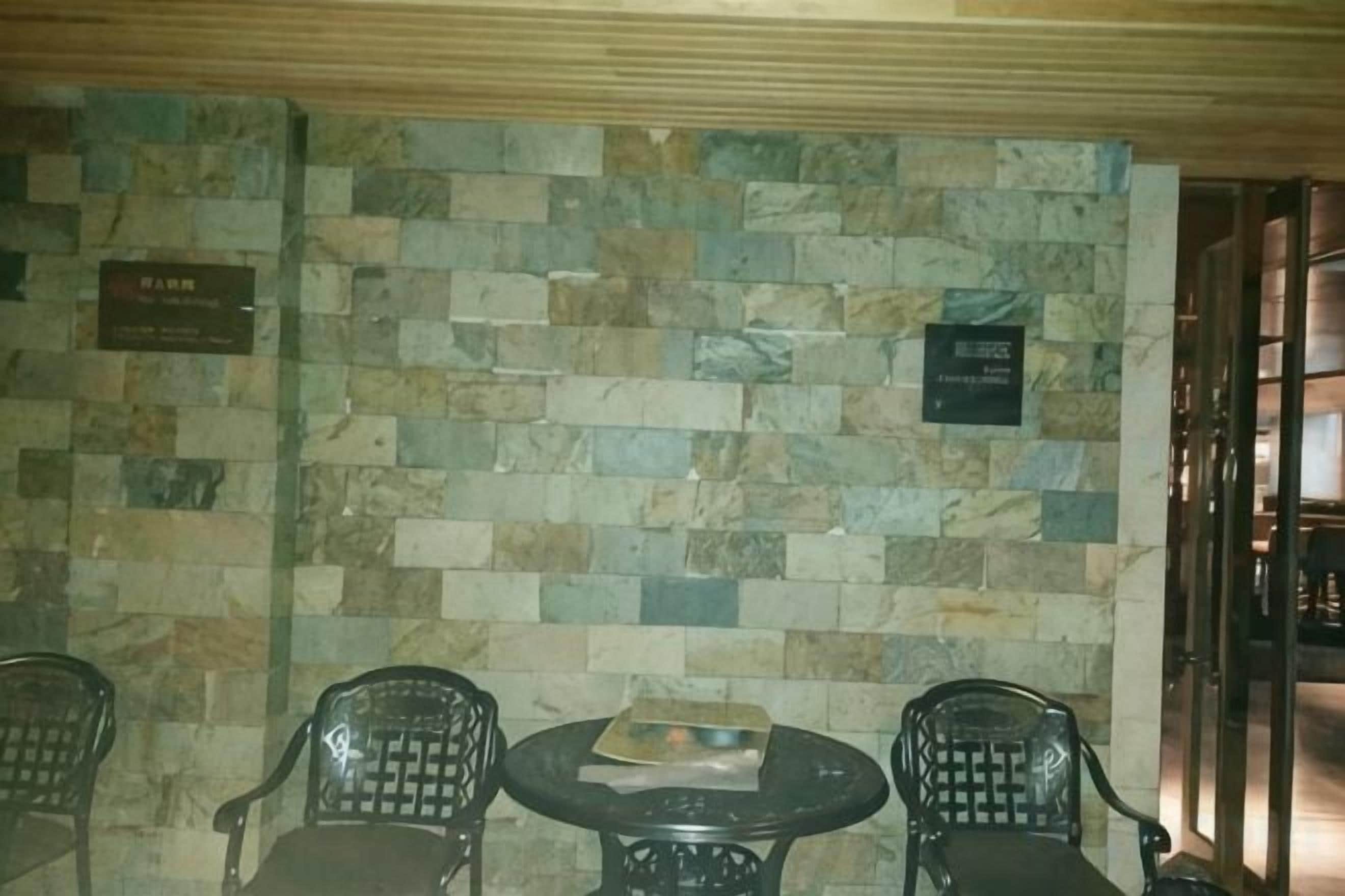 Quarto com parede de pedra, duas cadeiras e uma pequena mesa com uma caixa.