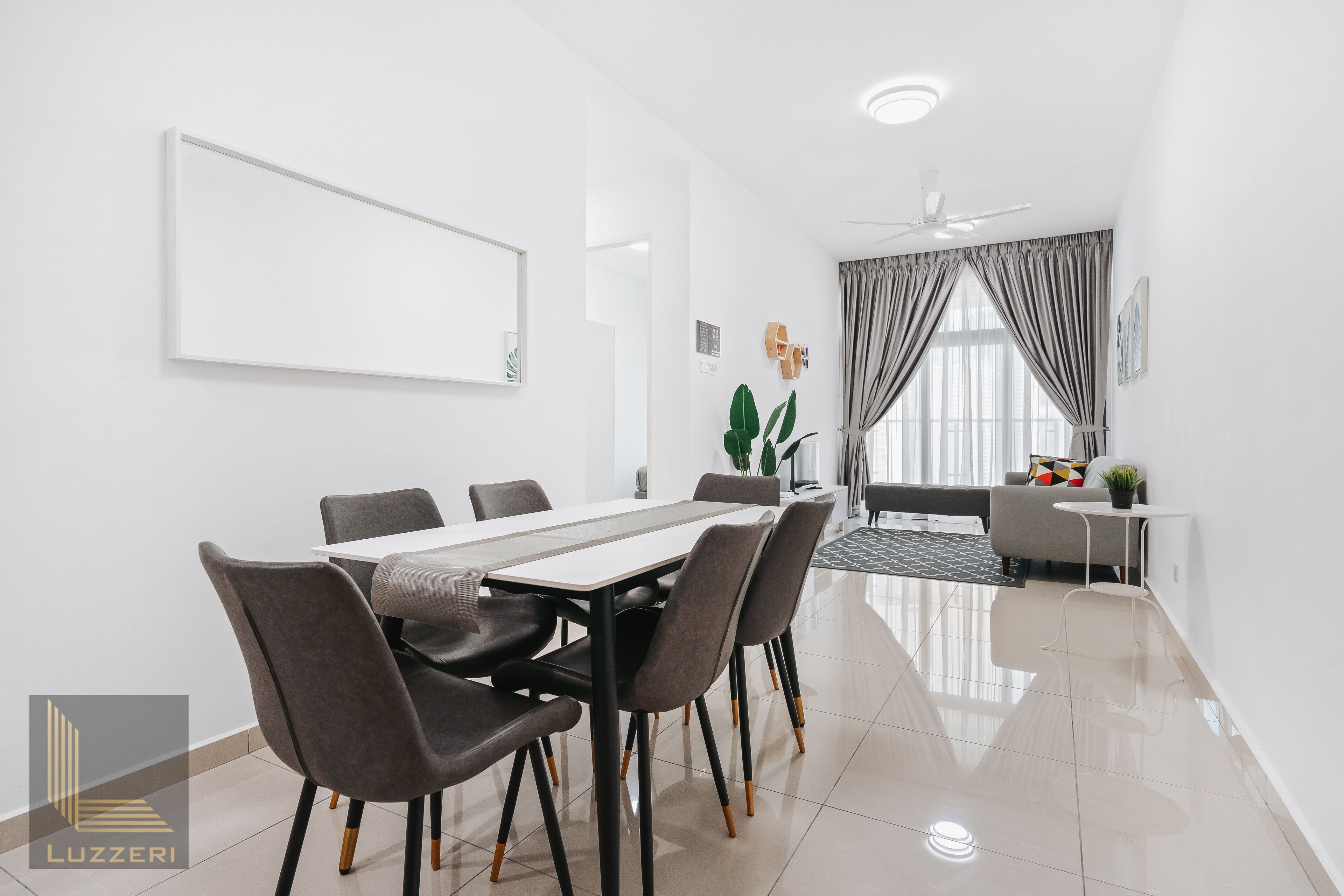 Uma sala de jantar moderna com uma mesa comprida e cadeiras, uma lousa na parede e um ventilador de teto.