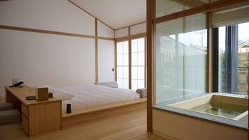 Quarto minimalista com escrivaninha de madeira, cama e uma janela grande.