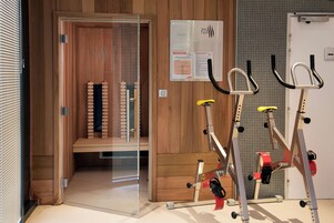 Um quarto de madeira com porta deslizante, equipamentos de ginástica e um letreiro informativo fixado na parede.