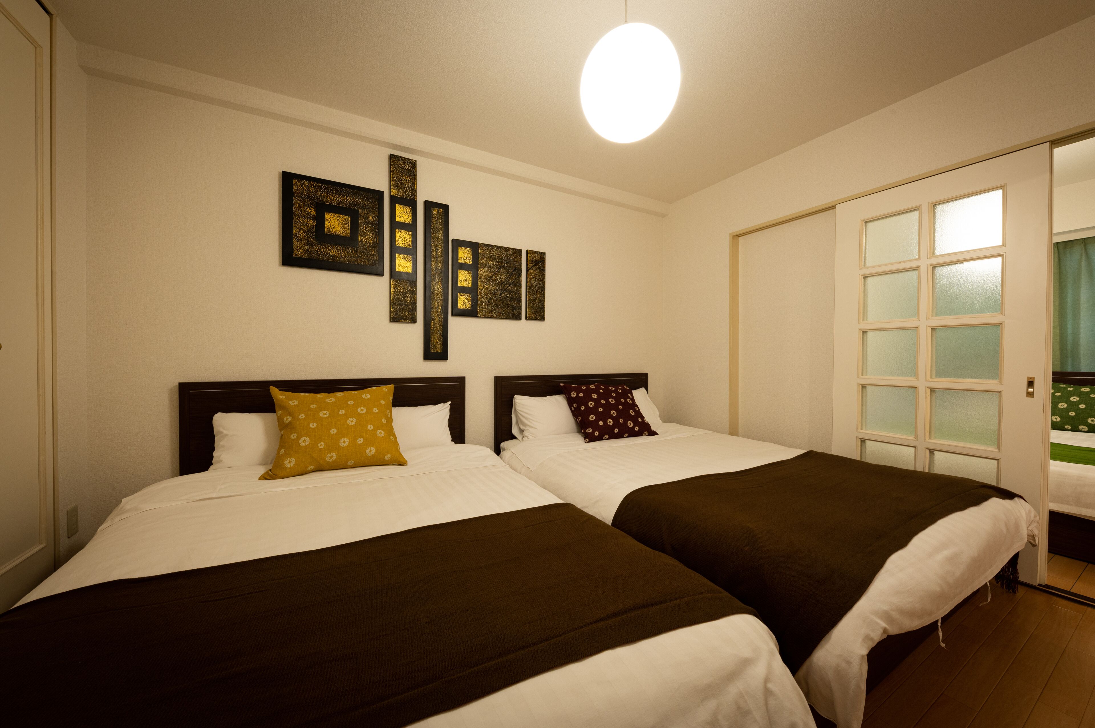 Quarto de hotel com duas camas, uma janela grande e porta que dá para uma varanda.