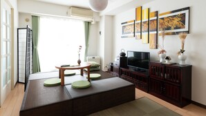 Uma sala de estar moderna com tatames, uma mesa baixa com almofadas, uma televisão e obras de arte na parede.