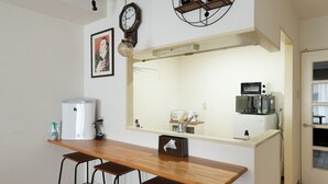 Cozinha compacta com bancada de madeira, dois bancos altos, geladeira, micro-ondas e pia.