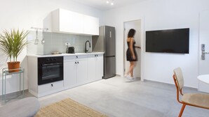 Uma cozinha moderna com armários brancos, uma geladeira de aço inoxidável e um forno embutido.