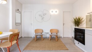 Uma cozinha moderna com área de refeições, com uma ilha central, duas cadeiras, uma mesa pequena e um luminário fixado na parede.
