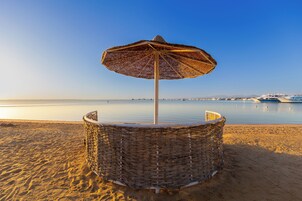 Praia particular, areia branca, espreguiçadeiras, guarda-sóis 