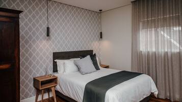 Quarto com cama, mesa de cabeceira de madeira e parede estampada.