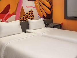 Quarto de hotel com duas camas, mesa de cabeceira, telefone e cadeira.