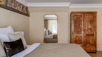Quarto com cama grande, guarda-roupa de madeira e espelho refletindo o aposento.