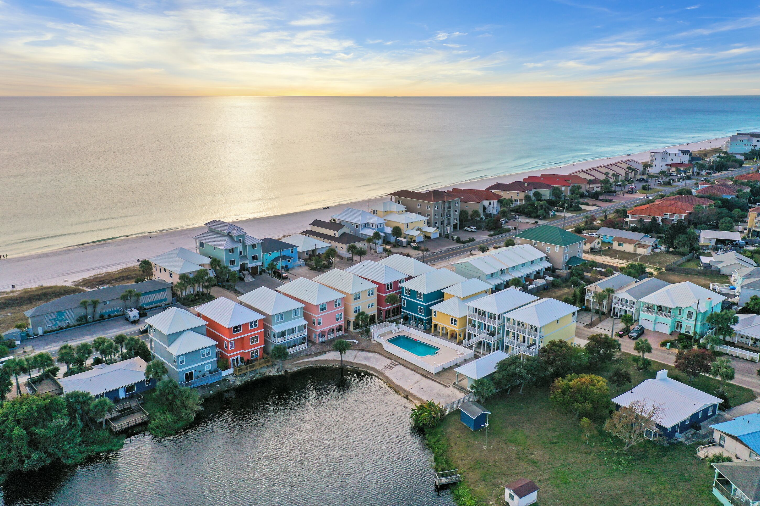 Uma área residencial costeira com casas coloridas, uma praia e um corpo d'água calmo.