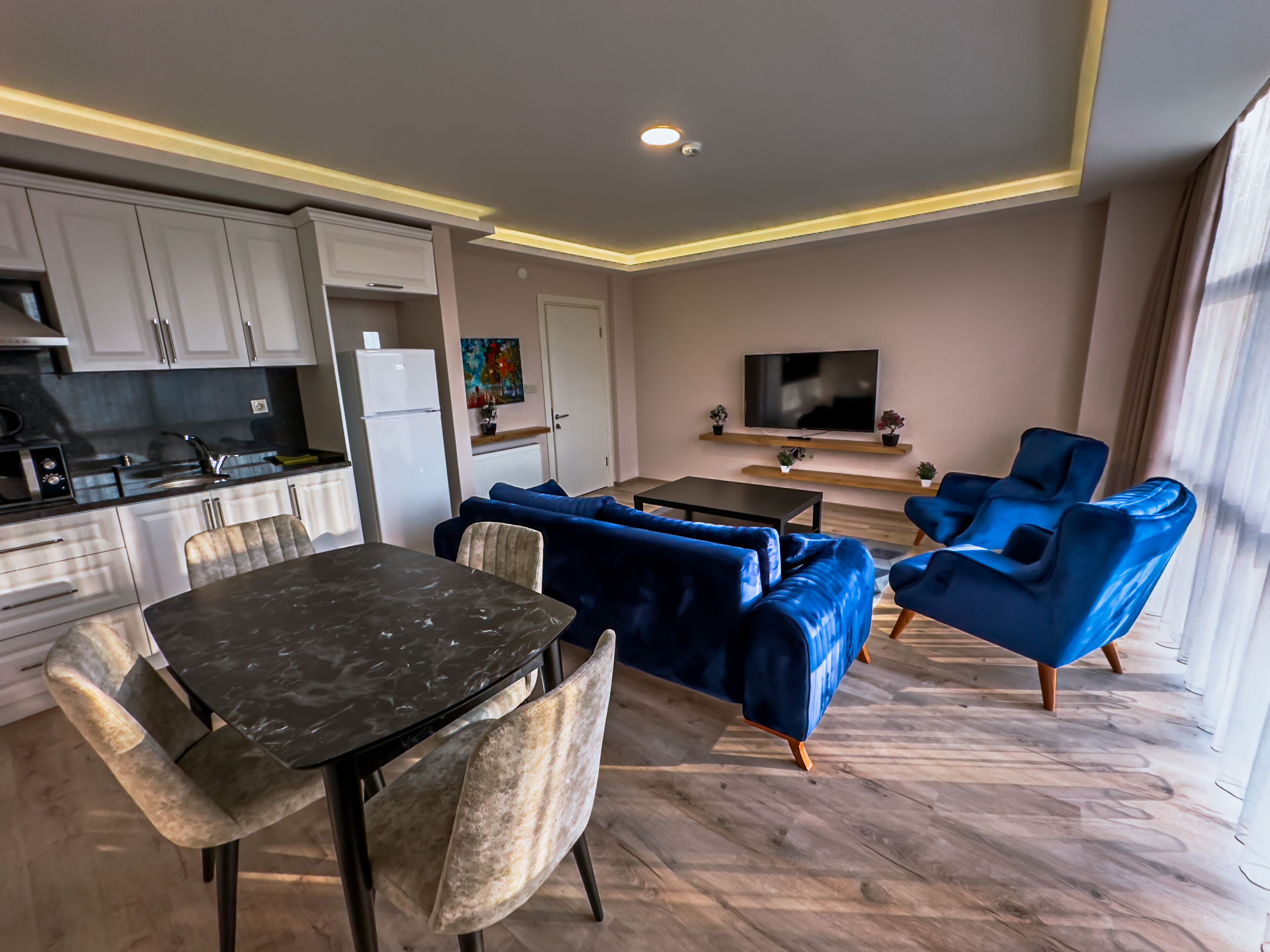 Uma sala moderna com área de jantar, cozinha e TV.