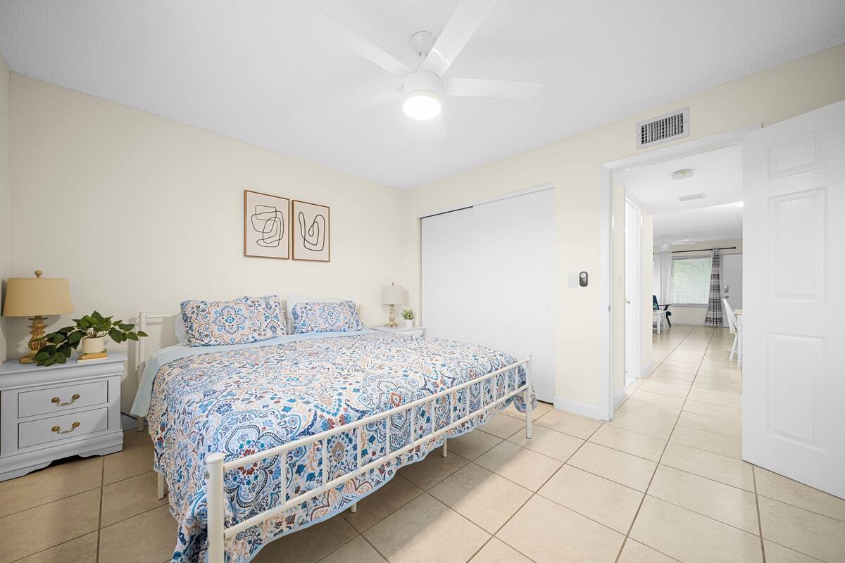 Quarto com cama, mesa de cabeceira, abajur e decoração na parede.