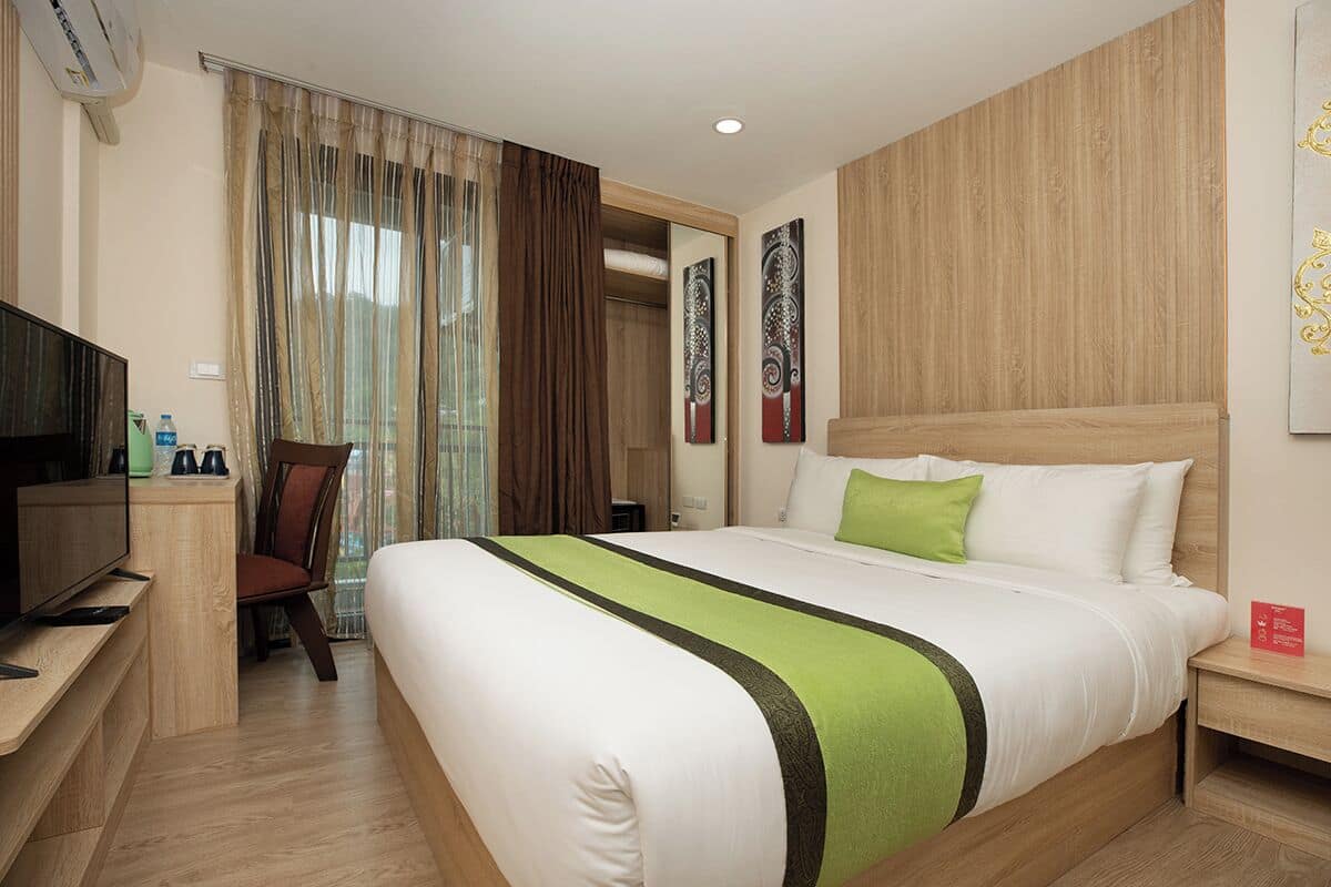Quarto de hotel com cama, televisão, escrivaninha e cadeira.