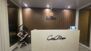 Uma receção com um letreiro a indicar "Casa Nova EL SUNZAL" num hall moderno com painéis de madeira e uma câmara de vigilância.