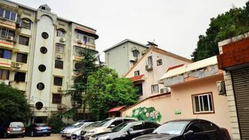 Fila de carros estacionados em área residencial, com edifícios altos ao fundo.