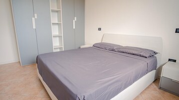 Um quarto com uma cama, um guarda-roupa e uma mesa de cabeceira.