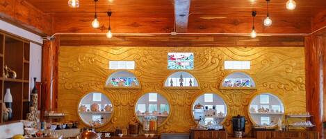 Interior de restaurante com paredes de madeira, lâmpadas pendentes e espelhos decorativos.