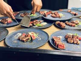 Um chef prepara pratos de bife em pratos azuis.