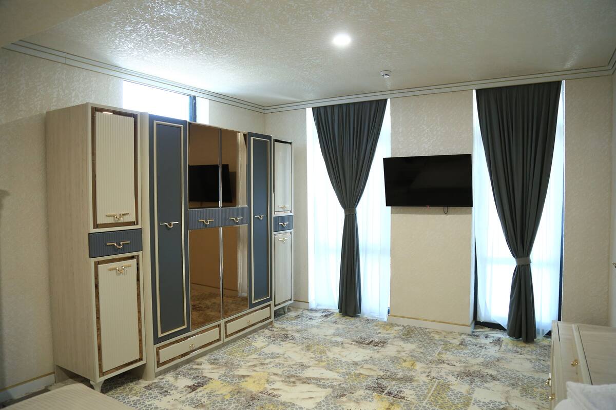 Quarto com um guarda-roupa espaçoso, televisão de tela plana na parede e carpete estampado.