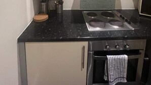 Uma cozinha compacta com fogão, forno e um pequeno armário com utensílios de cozinha.
