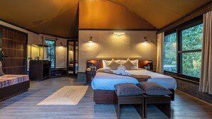 Um quarto espaçoso com uma cama grande, mesas de cabeceira, um banquinho e vista para o exterior.