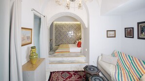 Um quarto com cama, sofá, lustre e papel de parede estampado.
