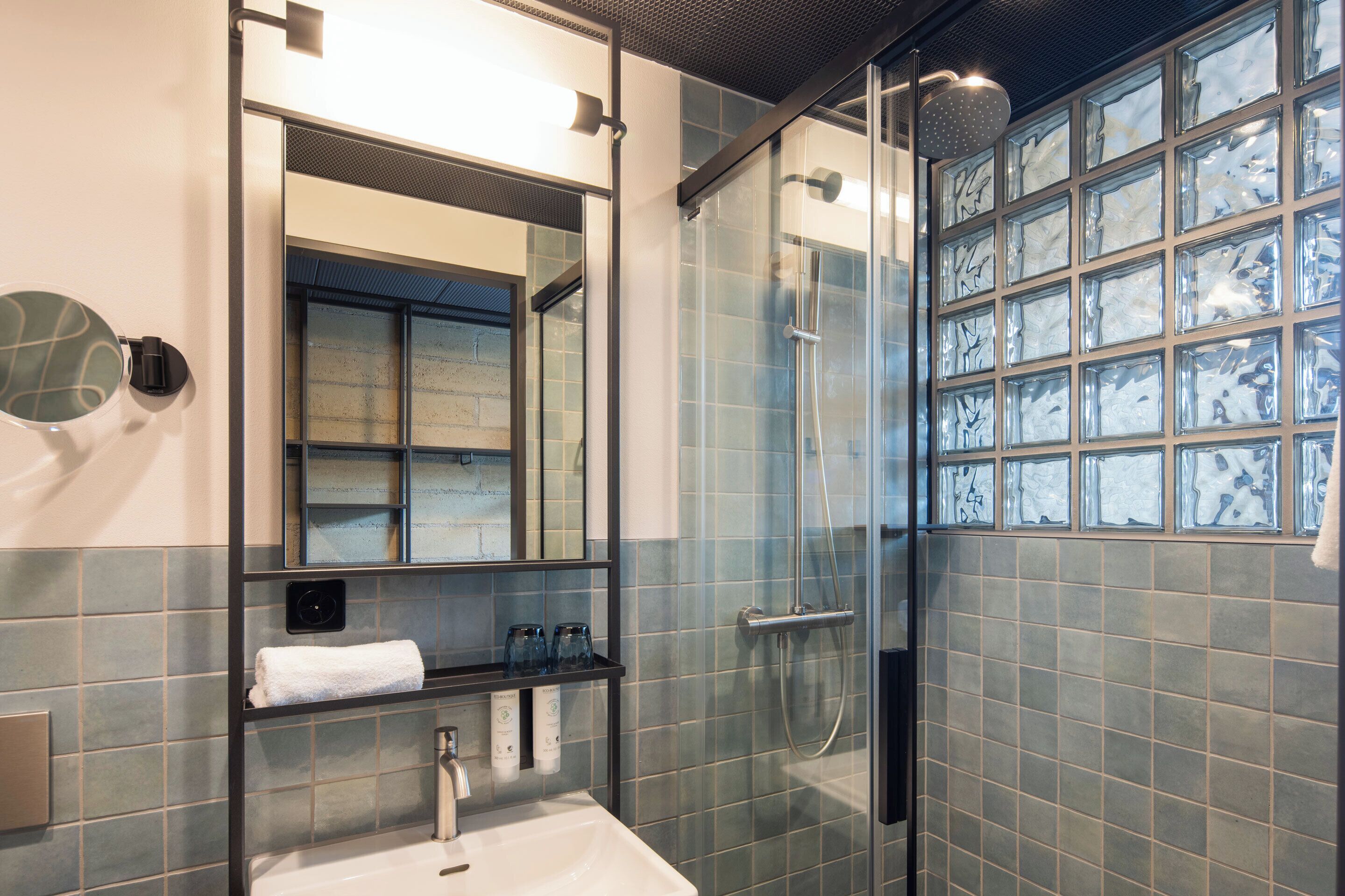 Uma casa de banho moderna com cabine de duche em vidro, um espelho grande e lavatório com porta-toalhas.