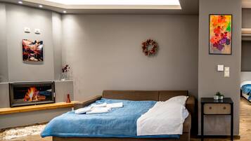 Quarto moderno com cama, lareira, mesa de cabeceira e parede com obras de arte.