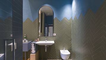 Uma casa de banho moderna com parede em padrão herringbone, uma pia, um bidé e cabine de duche em vidro.