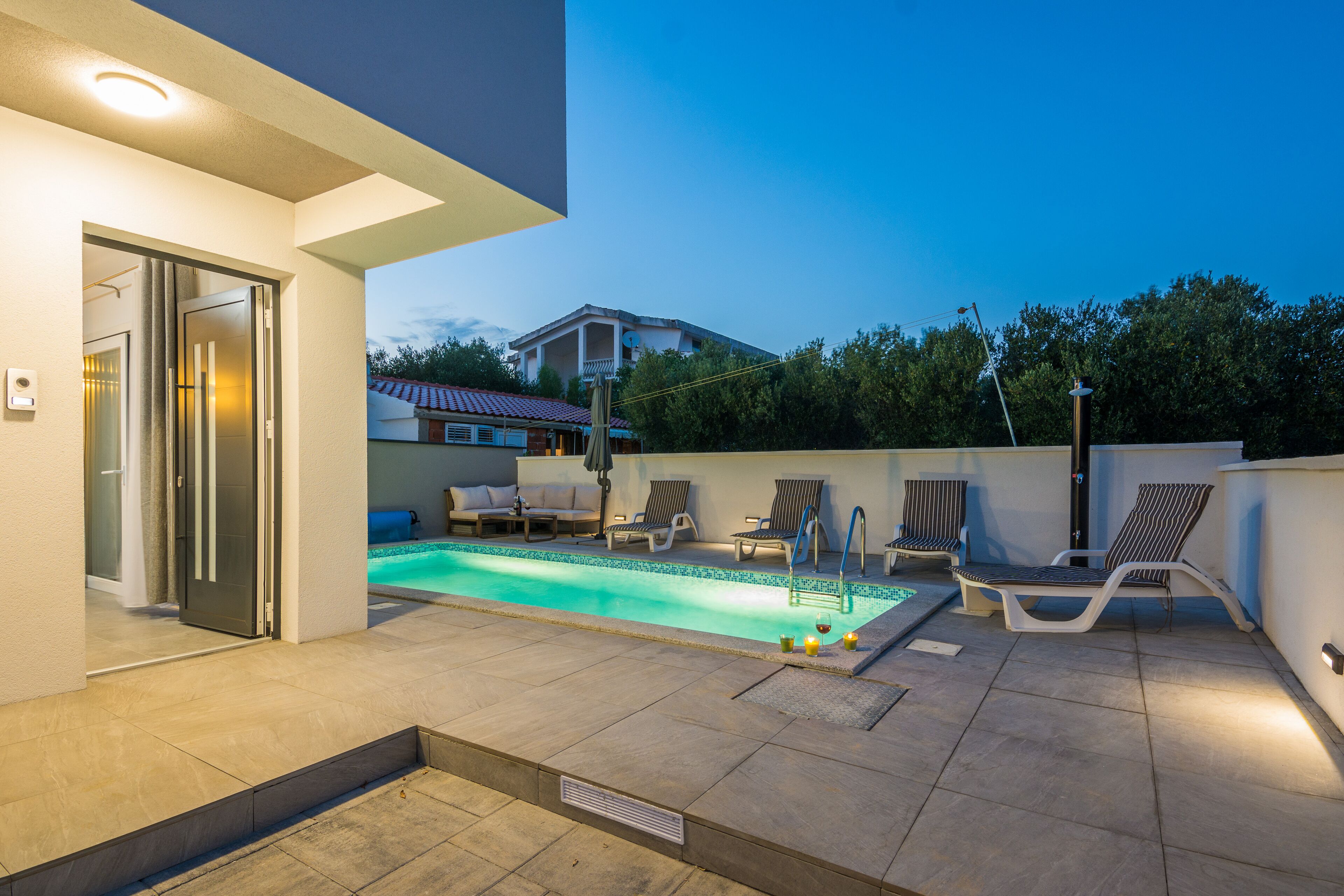 Uma área de piscina ao ar livre com espreguiçadeiras e uma porta que dá para um edifício.
