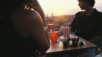Uma mesa com uma bebida, um copo listrado e uma planta verde.