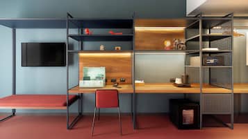 Quarto moderno com escrivaninha, cadeira, estantes e televisão.