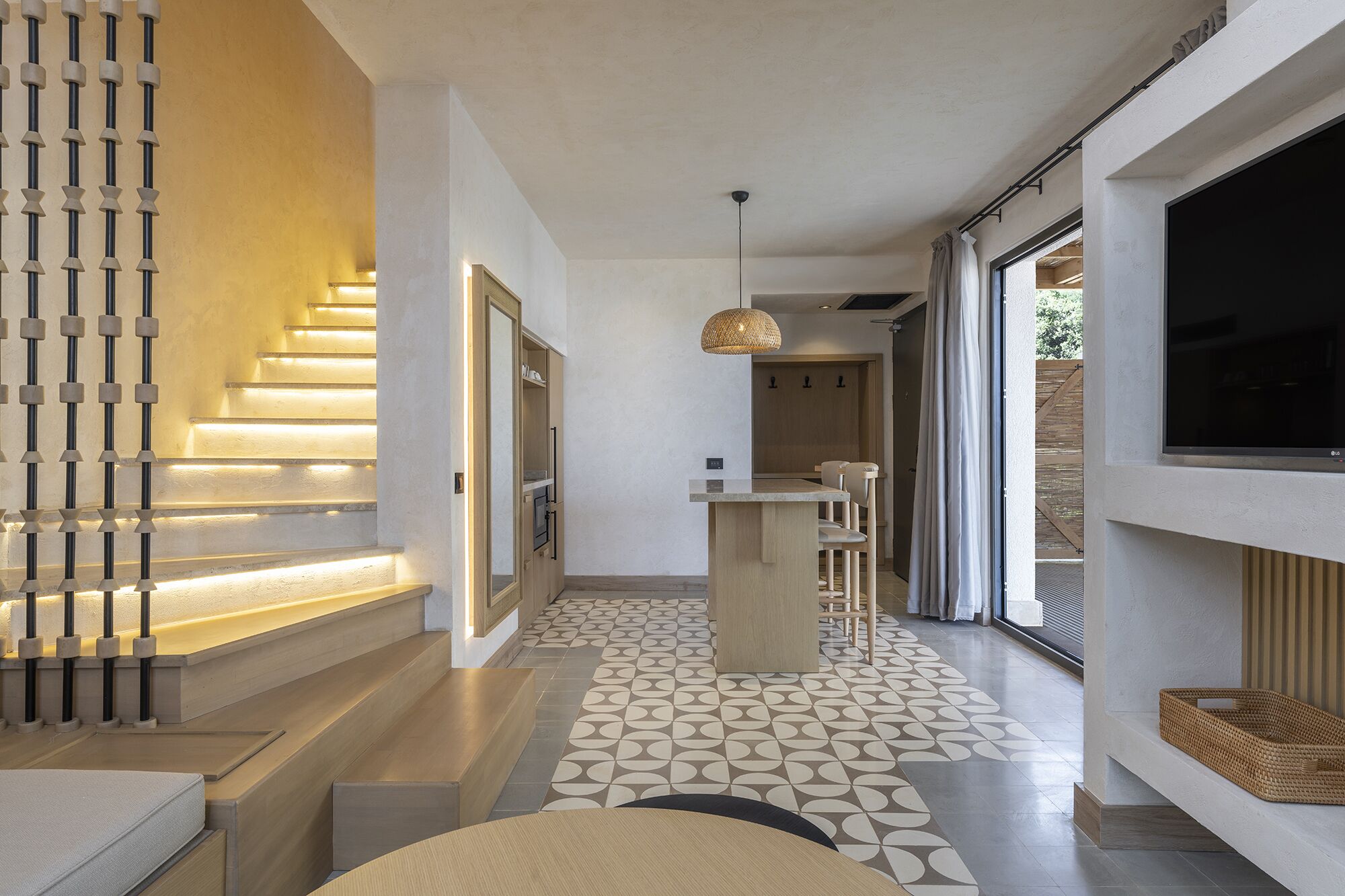 Um interior moderno com escada, ilha central com assentos e grandes janelas.