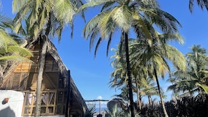 Um cenário tropical com um edifício de telhado de palha e palmeiras.