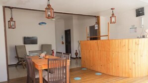 Uma sala de jantar com uma mesa e cadeiras de madeira, uma televisão e um balcão de madeira.