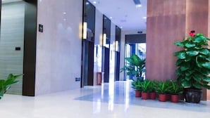 Um hall moderno com piso lustroso, colunas imponentes e plantas em vasos.