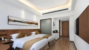 Quarto de hotel com duas camas, uma escrivaninha, uma cadeira, um telefone e um quadro na parede.
