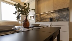 Uma cozinha moderna com painel de mármore, armários de madeira e uma mesa de jantar posta com pratos, um copo e um vaso.