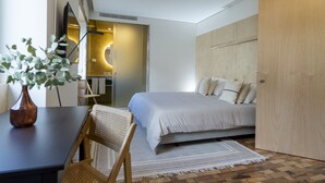 Quarto moderno com cama, escrivaninha, cadeira, guarda-roupa de madeira e uma pequena planta.