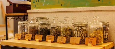 Exposição de chás com diversos tipos em potes de vidro identificados com nomes como 'Sporis Tea', 'Sipsuk Tea' e 'Thyme Tea'.