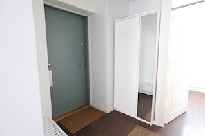 Um corredor com uma porta fechada, uma porta branca que dá para um armário e um tapete de entrada castanho.
