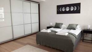 Um quarto com uma cama, uma mesinha de cabeceira, uma obra de arte na parede com as fases da lua e uma porta de vidro deslizante.