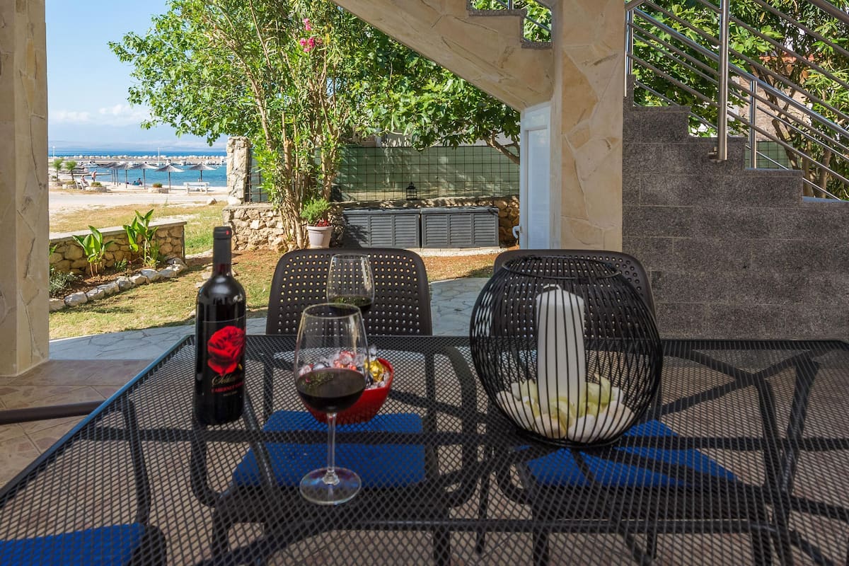 Uma área de estar ao ar livre com uma mesa, cadeiras e uma garrafa de vinho.