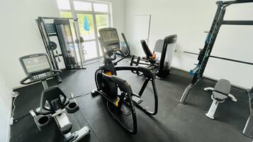 Academia com equipamentos de ginástica, incluindo bicicleta ergométrica, esteira e aparelhos de musculação.